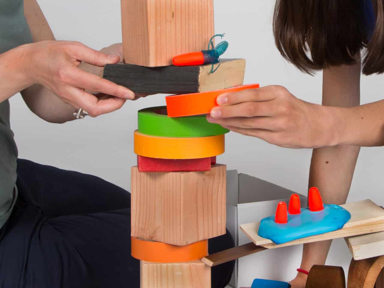 Closeup of Hands Building a Block and Disc Structure - DiscoverE